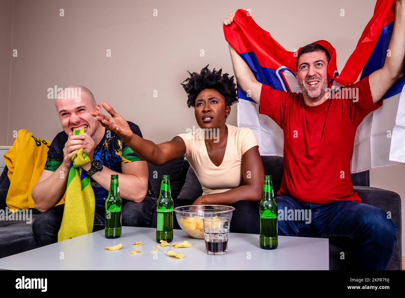 Friends watching a football match on TV, cheering for their national ...