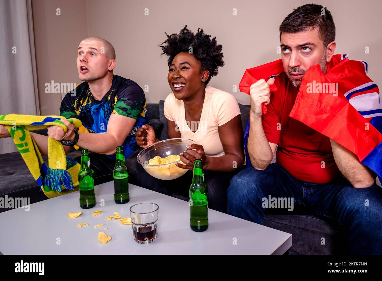 Friends watching a football match on TV, cheering for their national ...