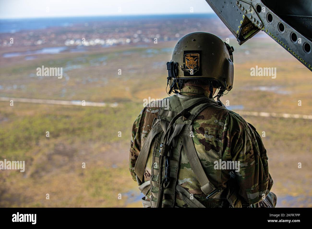 A Florida National Guard (FLNG) crew chief sits upon the ramp of a CH ...