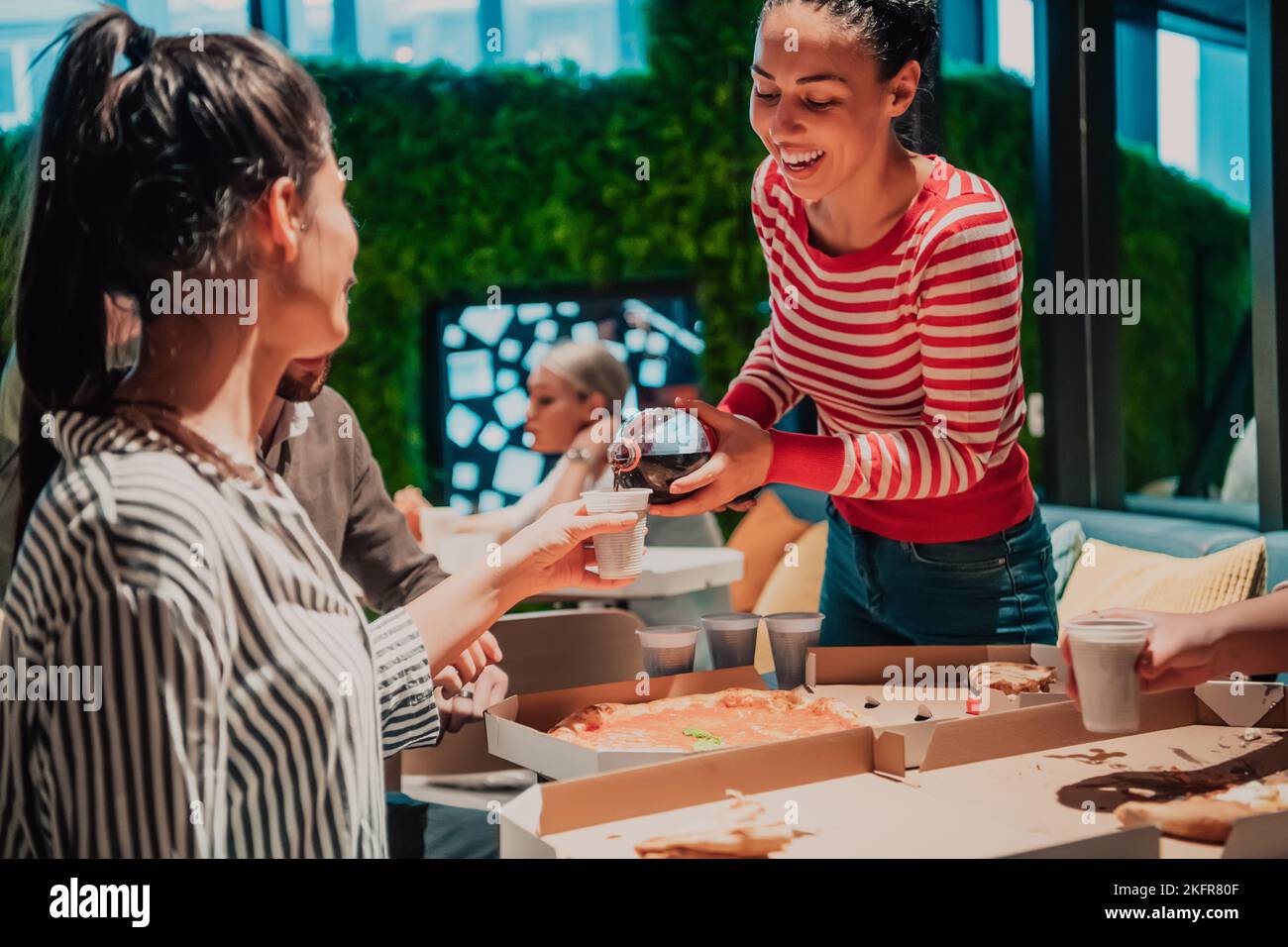 Eating pizza with diverse colleagues in the office, happy multi-ethnic ...