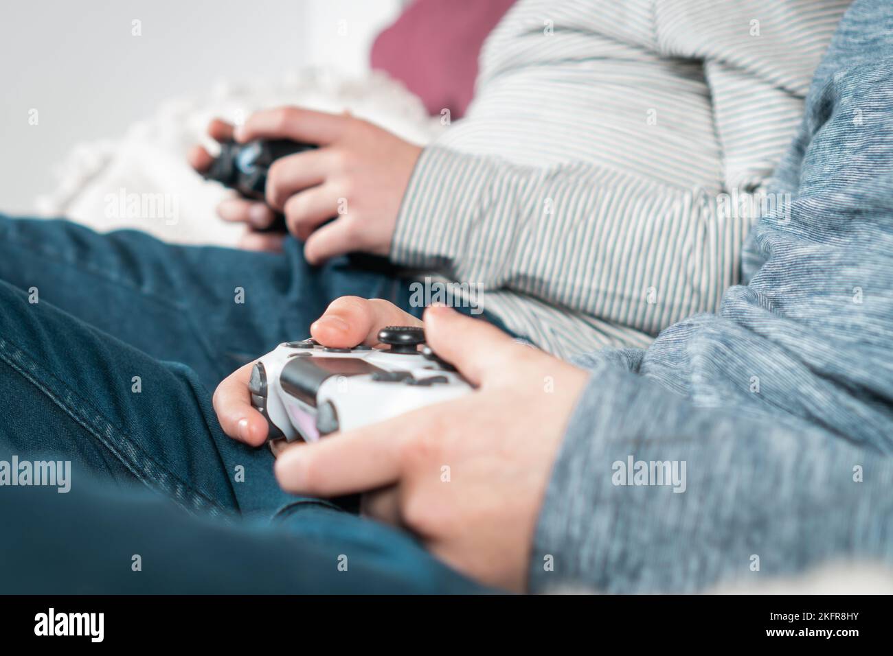 Cropped photo of two teenage boys children sitting at home, holding ...