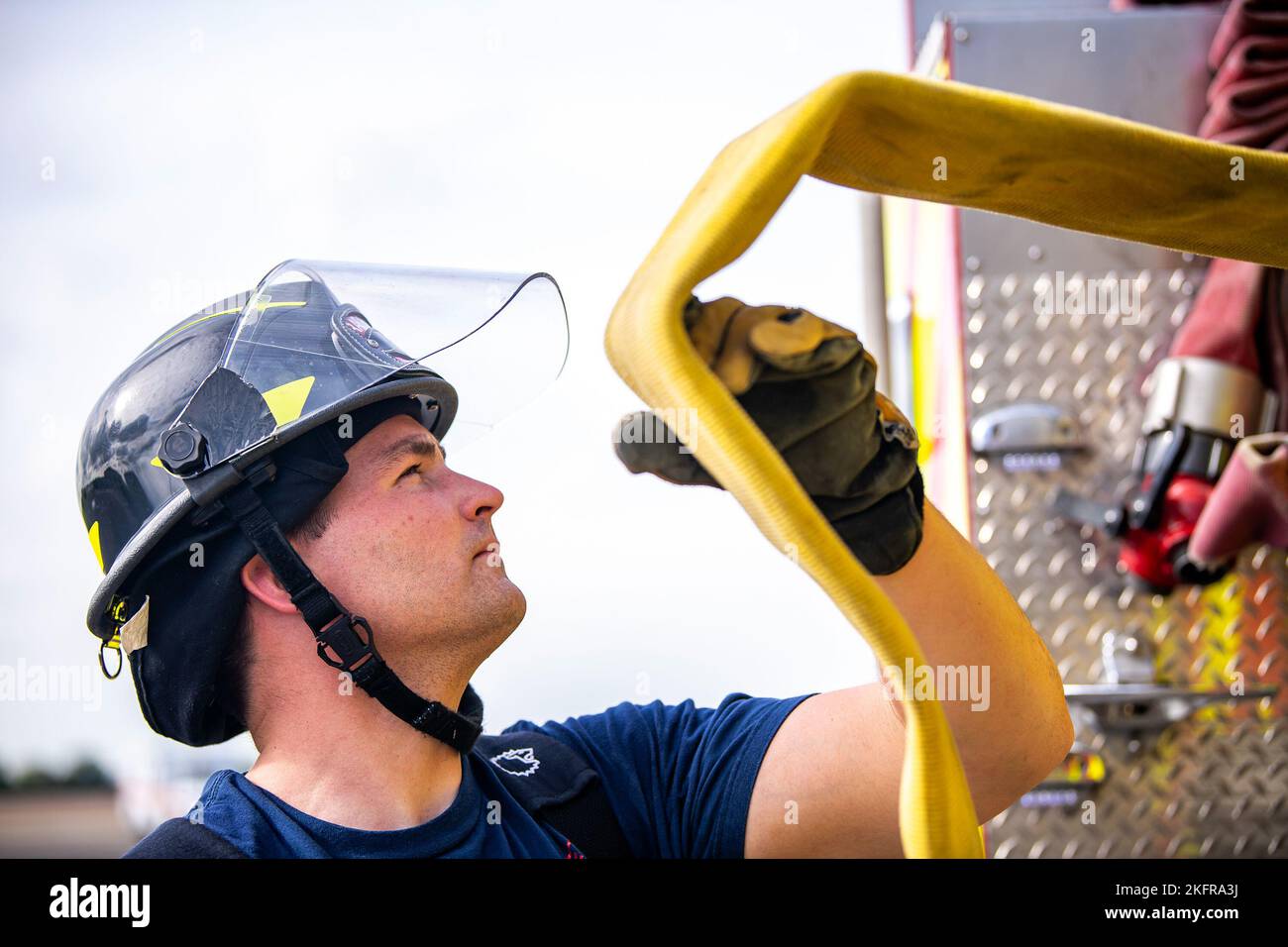 A firefighter from the 422d Fire Emergency Services rolls a fire hose ...