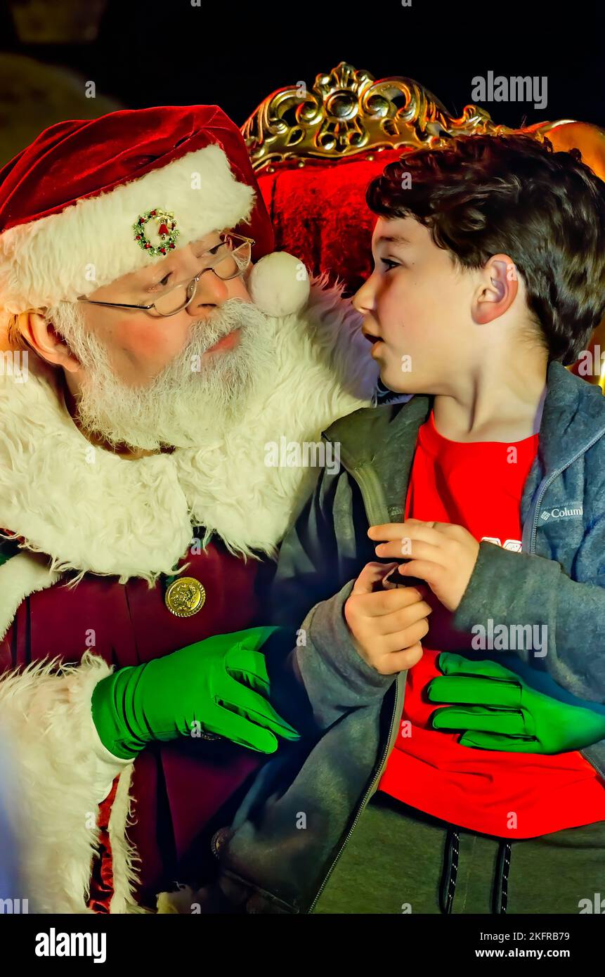 A little boy sits on Santa’s lap during the city Christmas tree ...