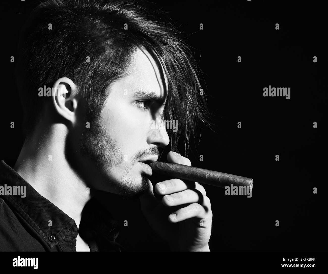 serious bearded man smoking cigar in black studio background Stock ...