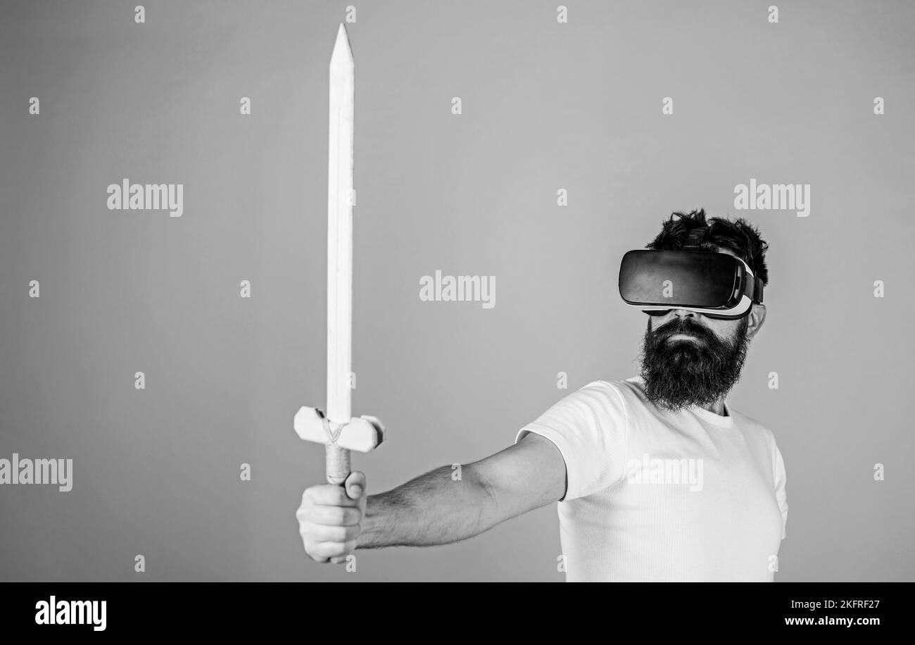Gamer concept. Guy with head mounted display holds sword, play fighting ...