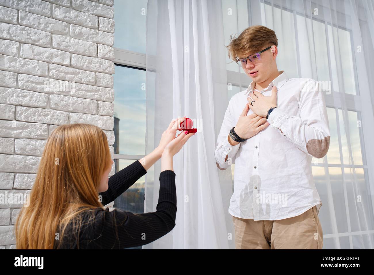 Embarrassing moment. Young woman holding box with engagement ring ...