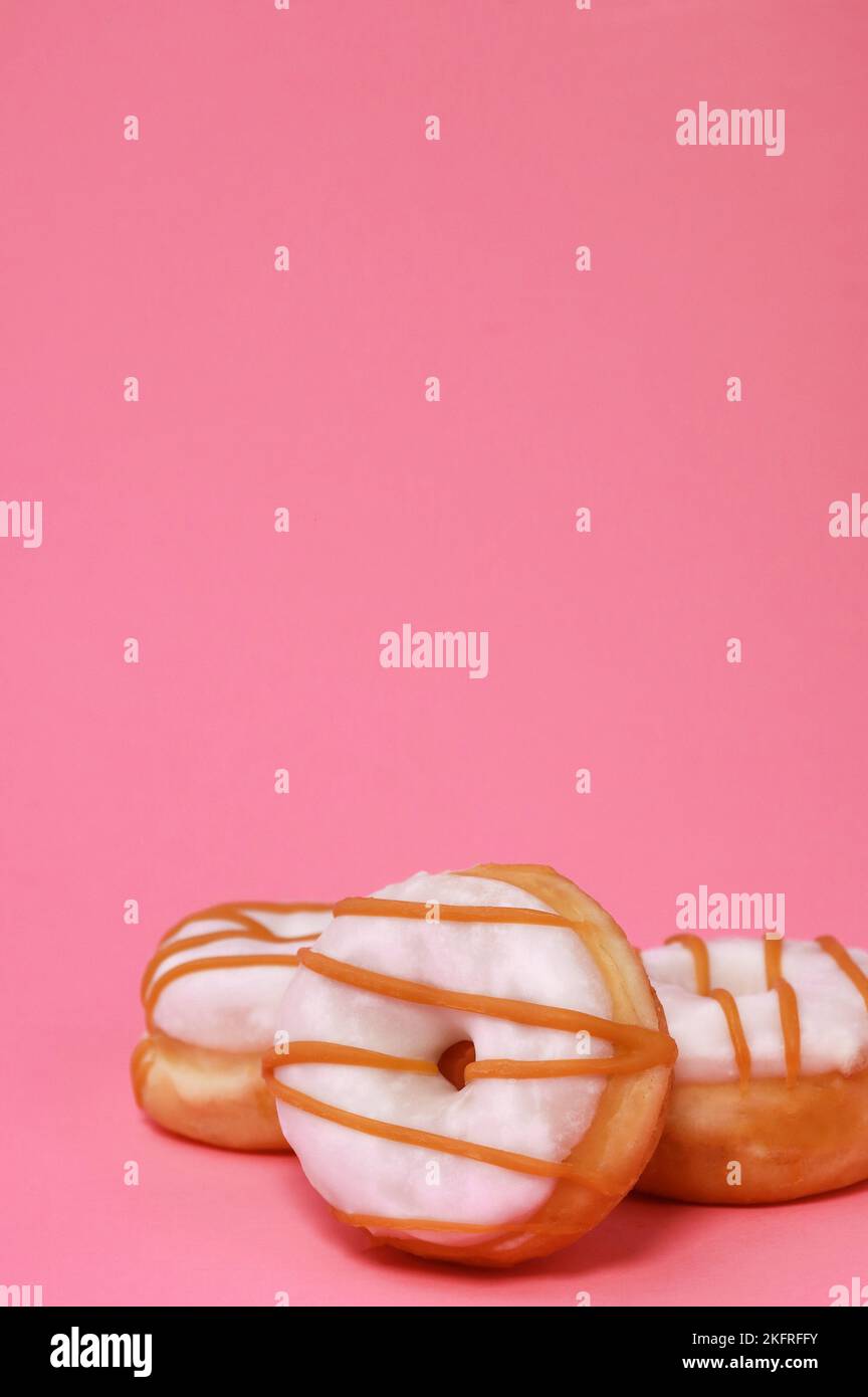 mini donuts with white glaze on pink background Stock Photo - Alamy