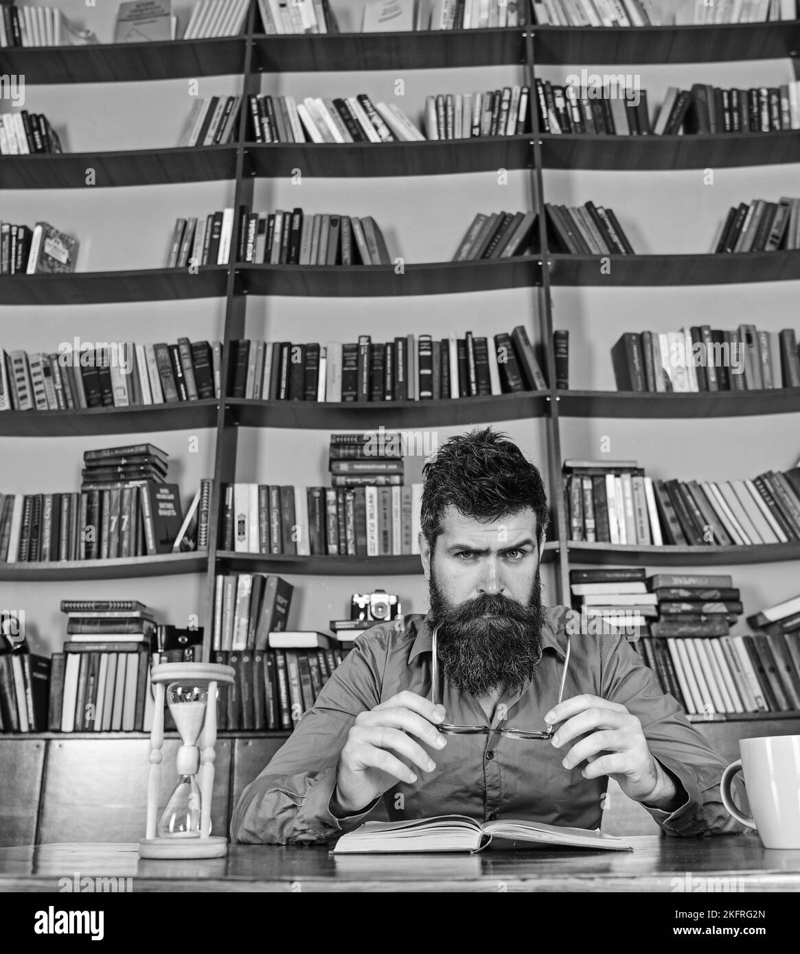 Man on busy face reading book, bookshelves on background. Education and ...
