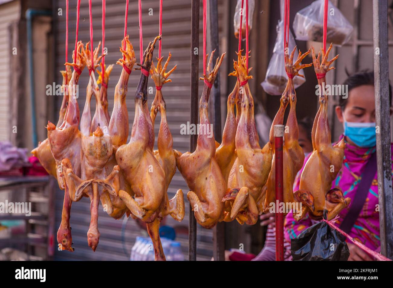 A Cambodian woman, wearing a protective face mask, sells whole, raw ...