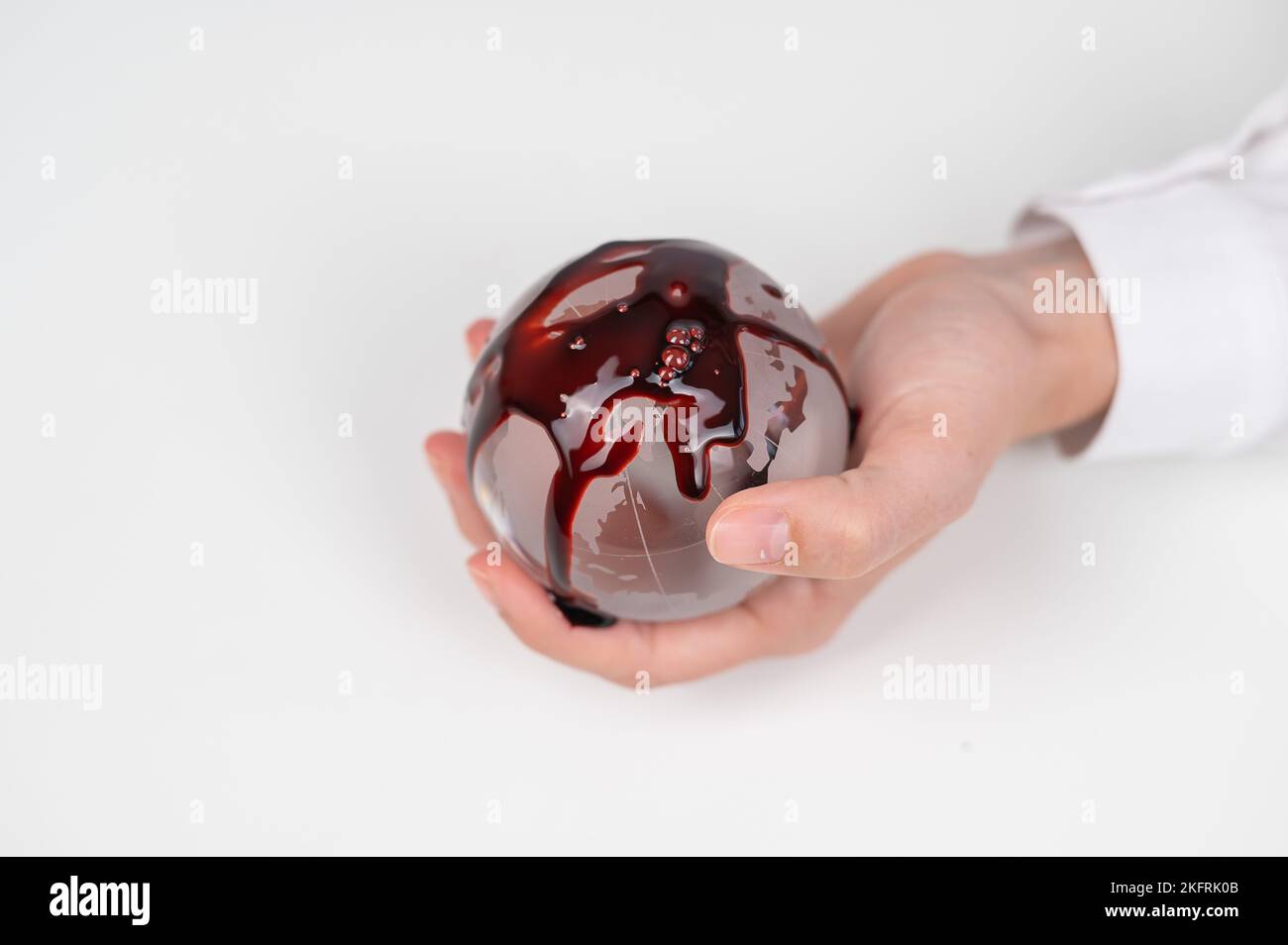 A woman holds a crystal globe smeared in blood on a white background ...