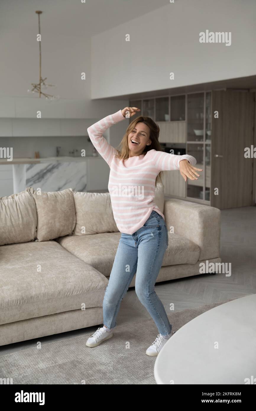 Happy carefree young woman having fun dancing alone at home Stock Photo ...
