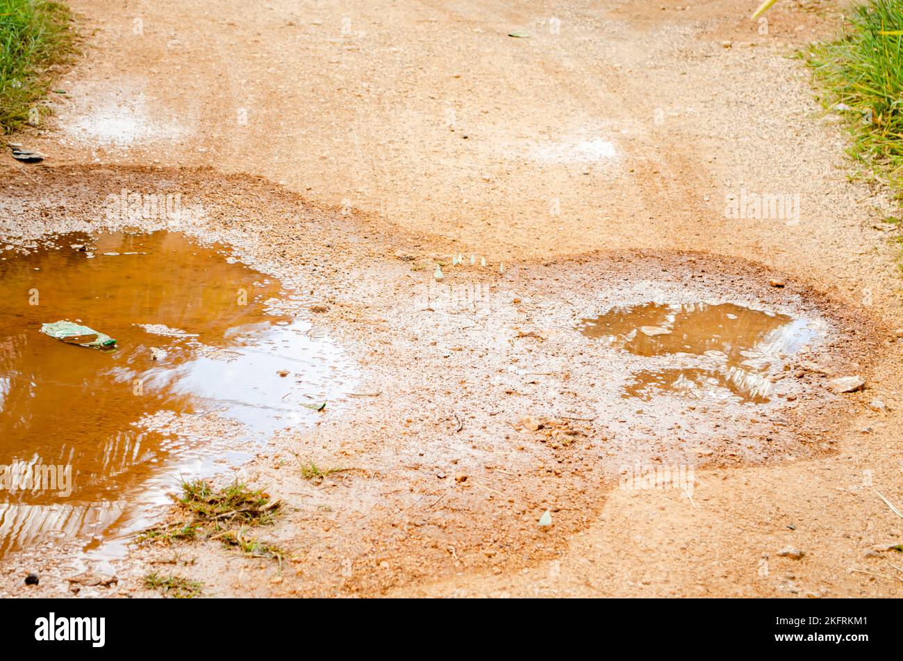 A large puddle of water spands the narrow marled roadway Stock Photo ...