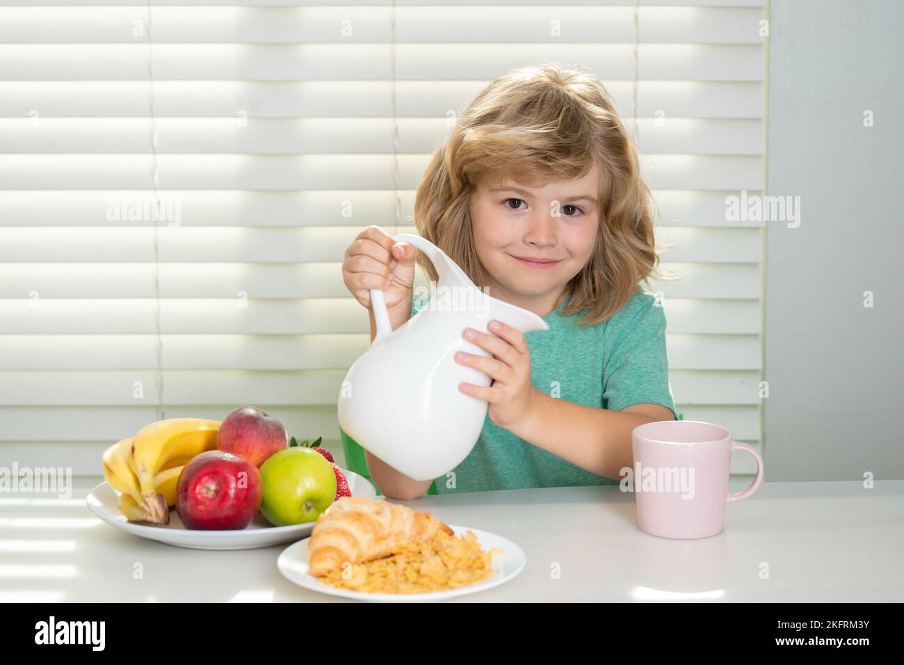 Fuuny little boy pouring whole cows milk for breakfast. Funny blonde ...