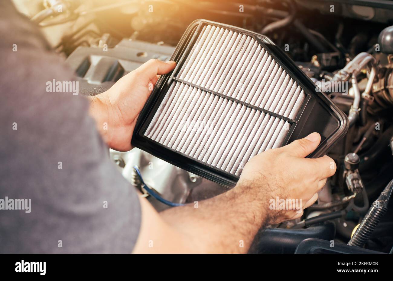 A auto mechanic carries a replacement car air filter for car engine ...