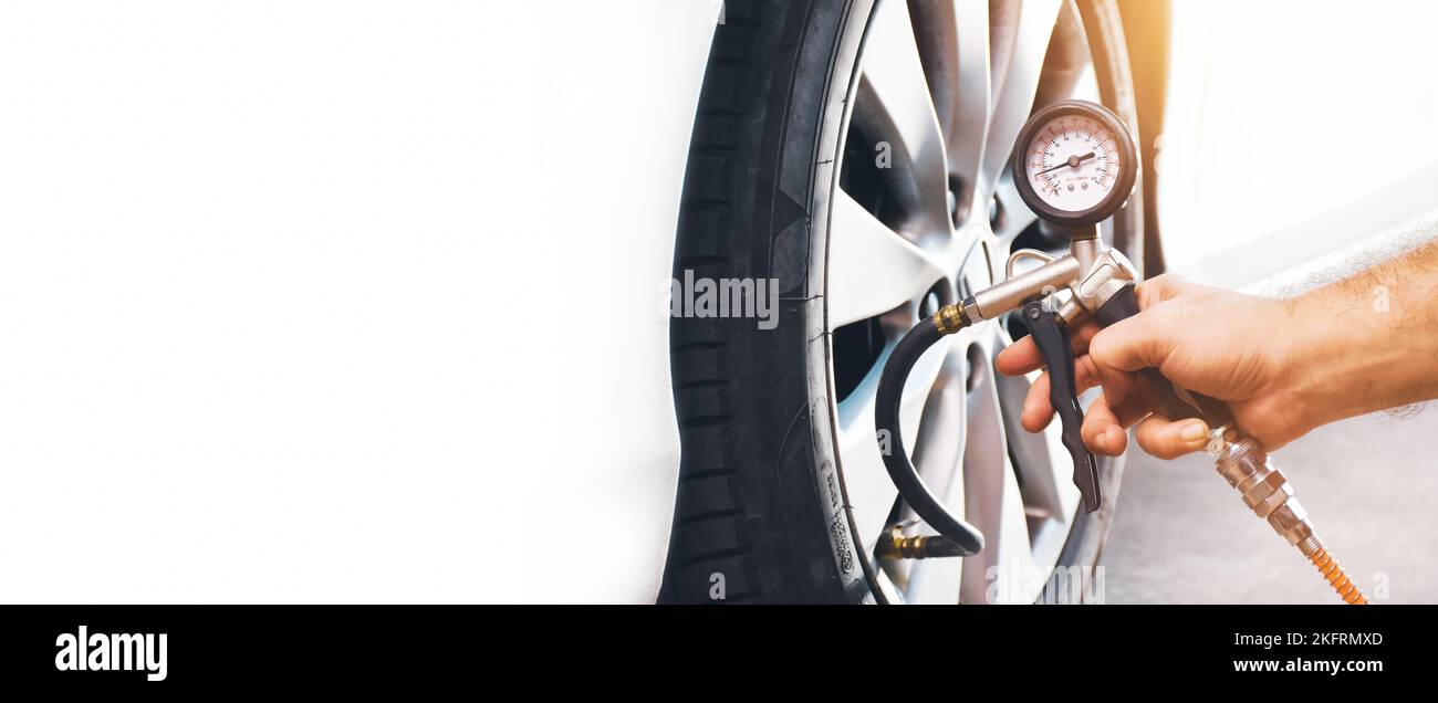 A auto mechanic inflates a tire with an air tire inflating gun ...