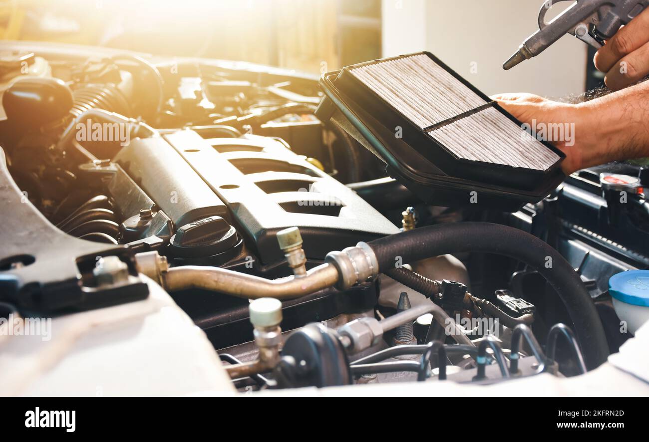 Car air filter in auto mechanic hand is blowing dust and cleaning with ...