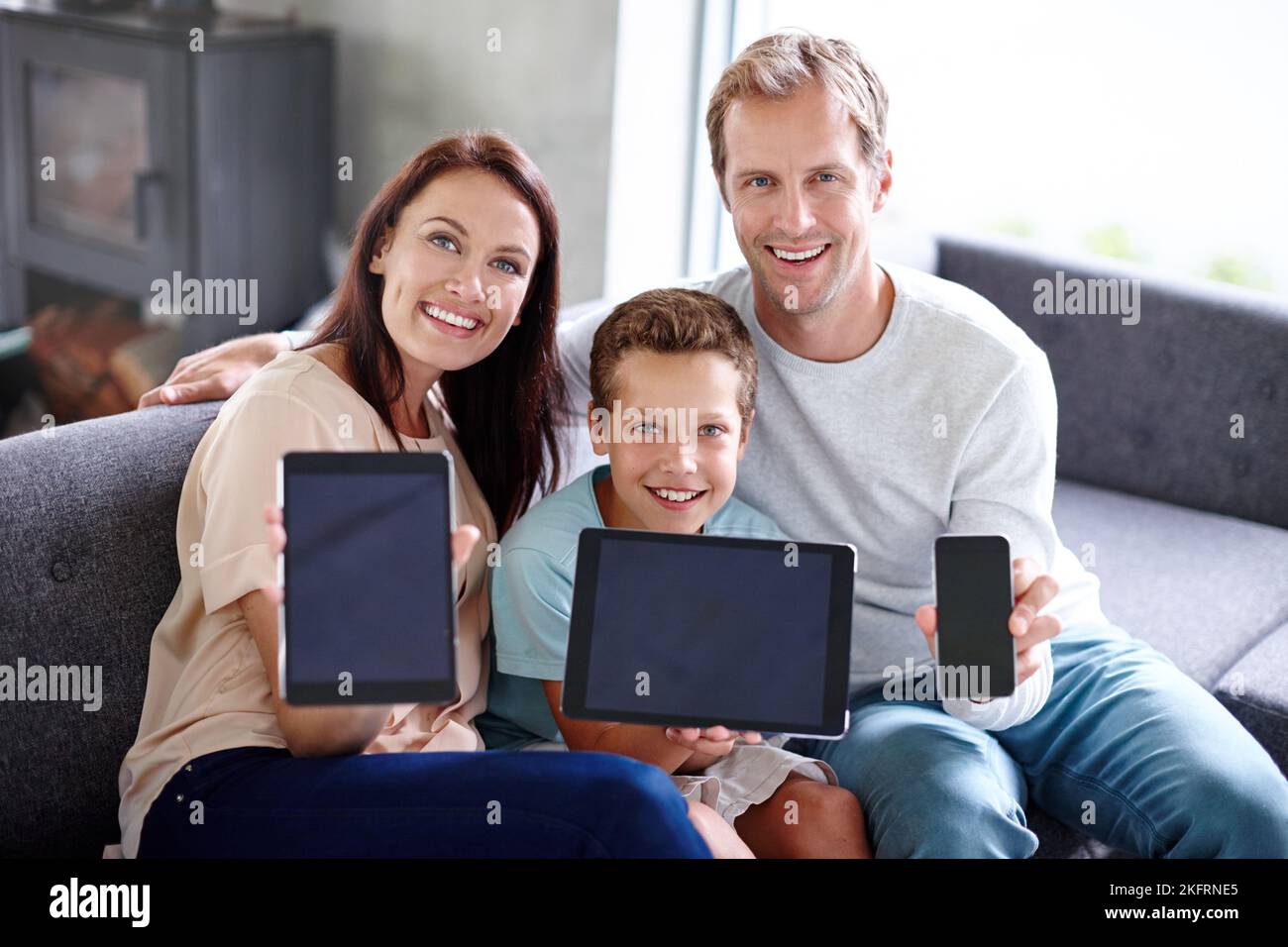 Check out our family tech. Portrait of a happy family holding up their ...