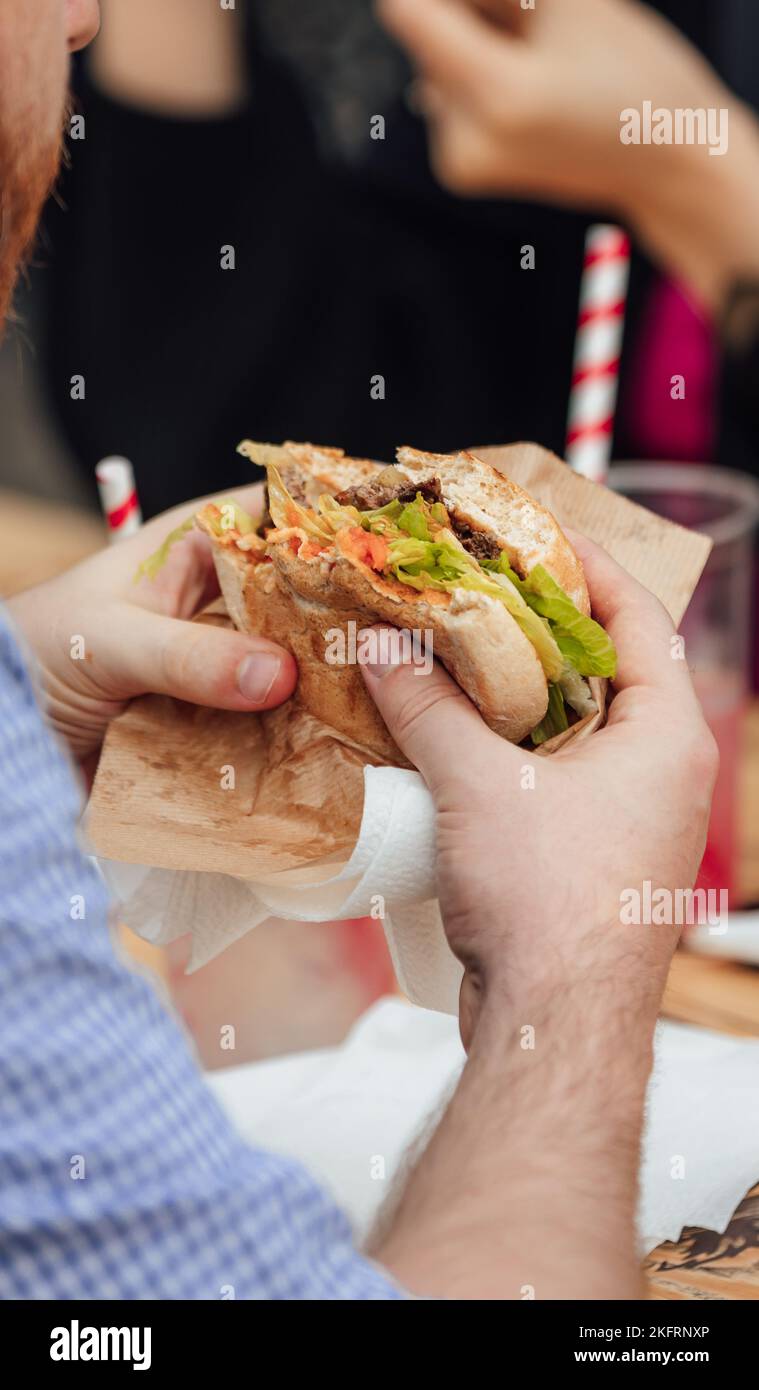 A man eating burger at the festival food court Stock Photo - Alamy