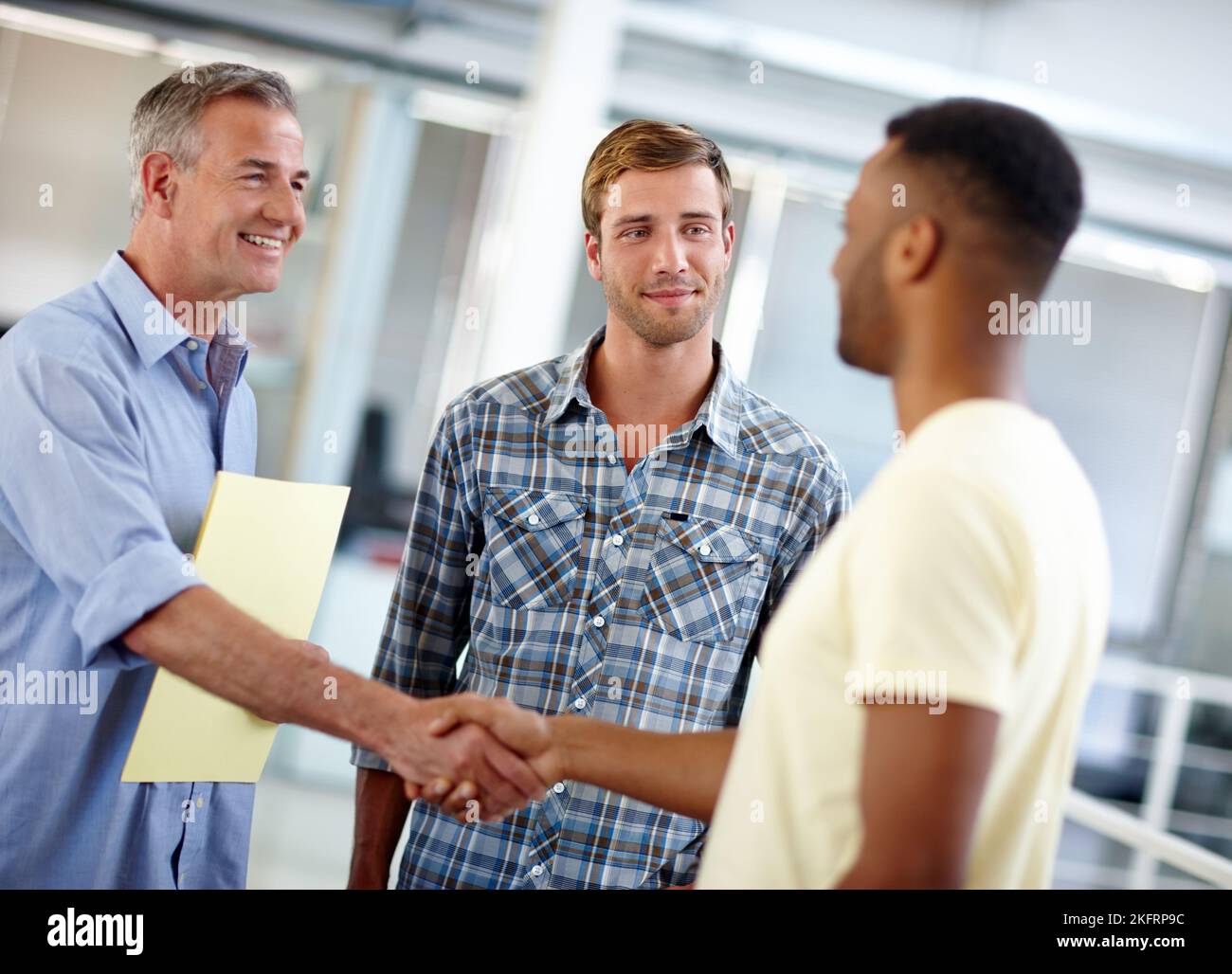 You made a good impression. a young man shaking hands with his coworker ...