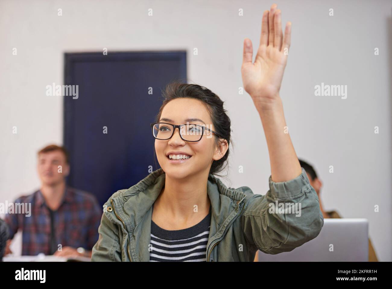 Making the most of her education. a young woman raising her hand to ask ...