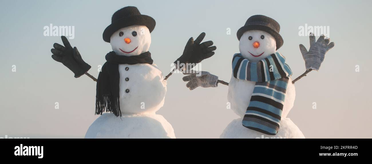 Two snow man holding hands outdoors. Winter snowman in black hat, scarf ...