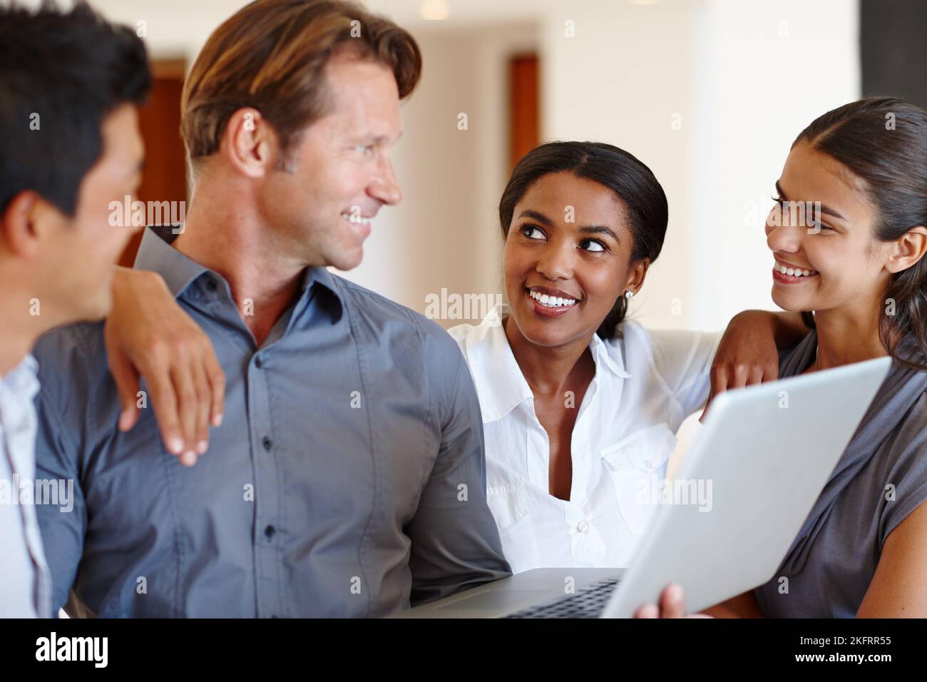 Great job team. a group of office workers standing around a laptop ...