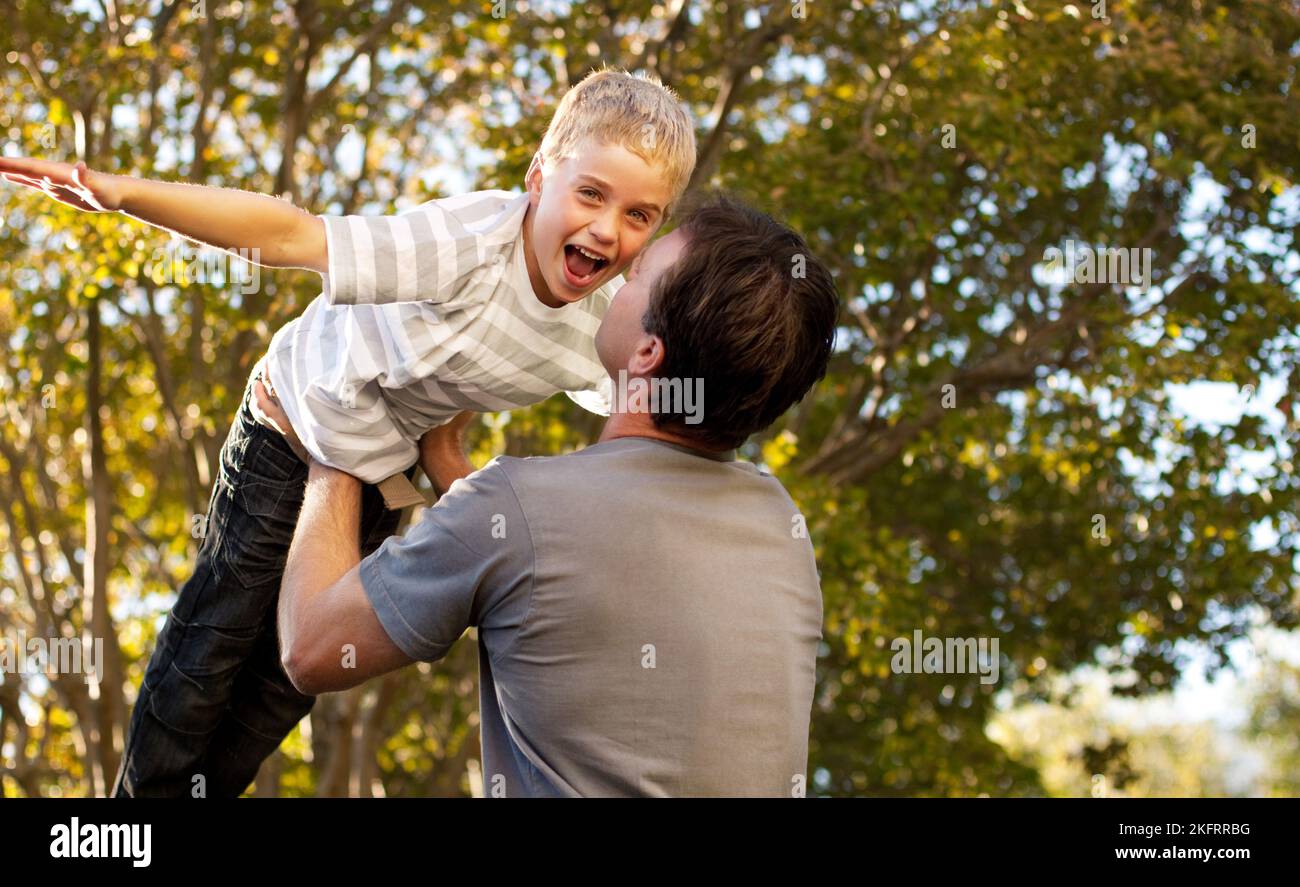 Aeroplane rides. Young father playing with his son, picking him up to ...
