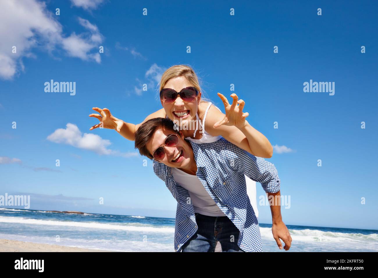 Sunny funnies. a happy young couple enjoying a piggyback ride at the ...