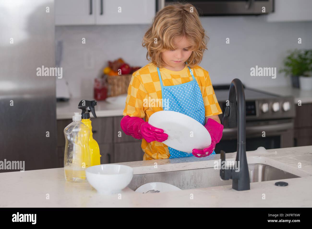 Kid wiping dishes in kitchen. Child cleaning and doing housework at ...