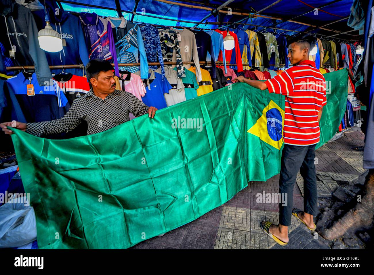 A shopkeeper displays the flag of Brazil to a customer, a participating ...