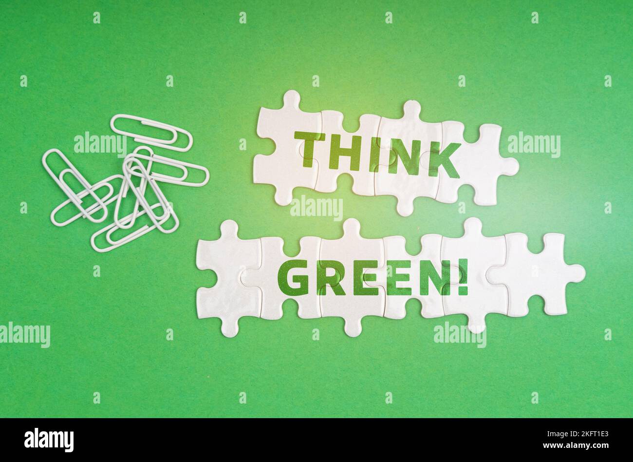Ecology concept. On a green background, paper clips and white puzzles ...