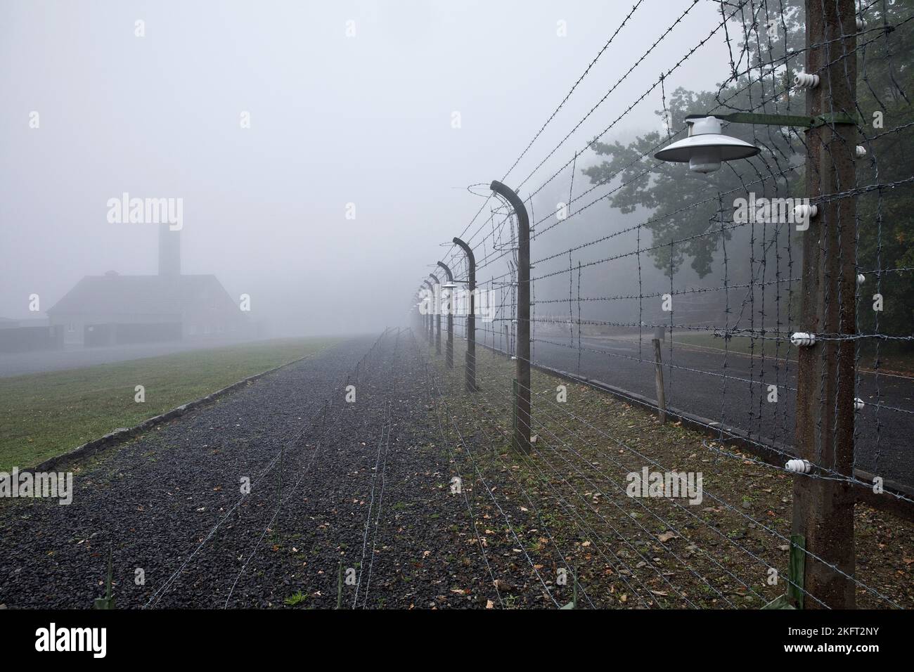 Reconstructed camp fence with crematorium in the fog at beech forest ...