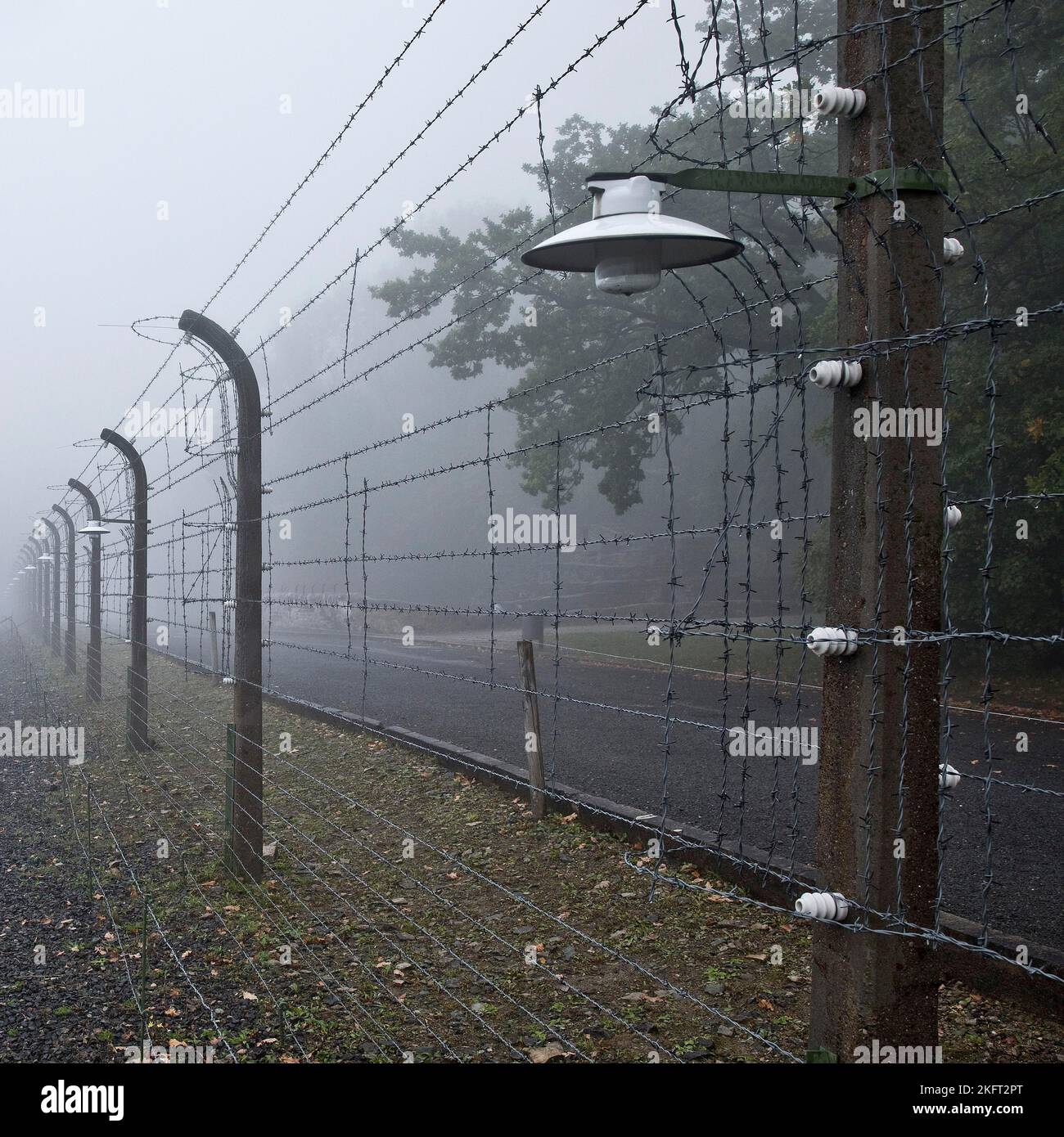 Reconstructed camp fence with crematorium in the fog at beech forest ...