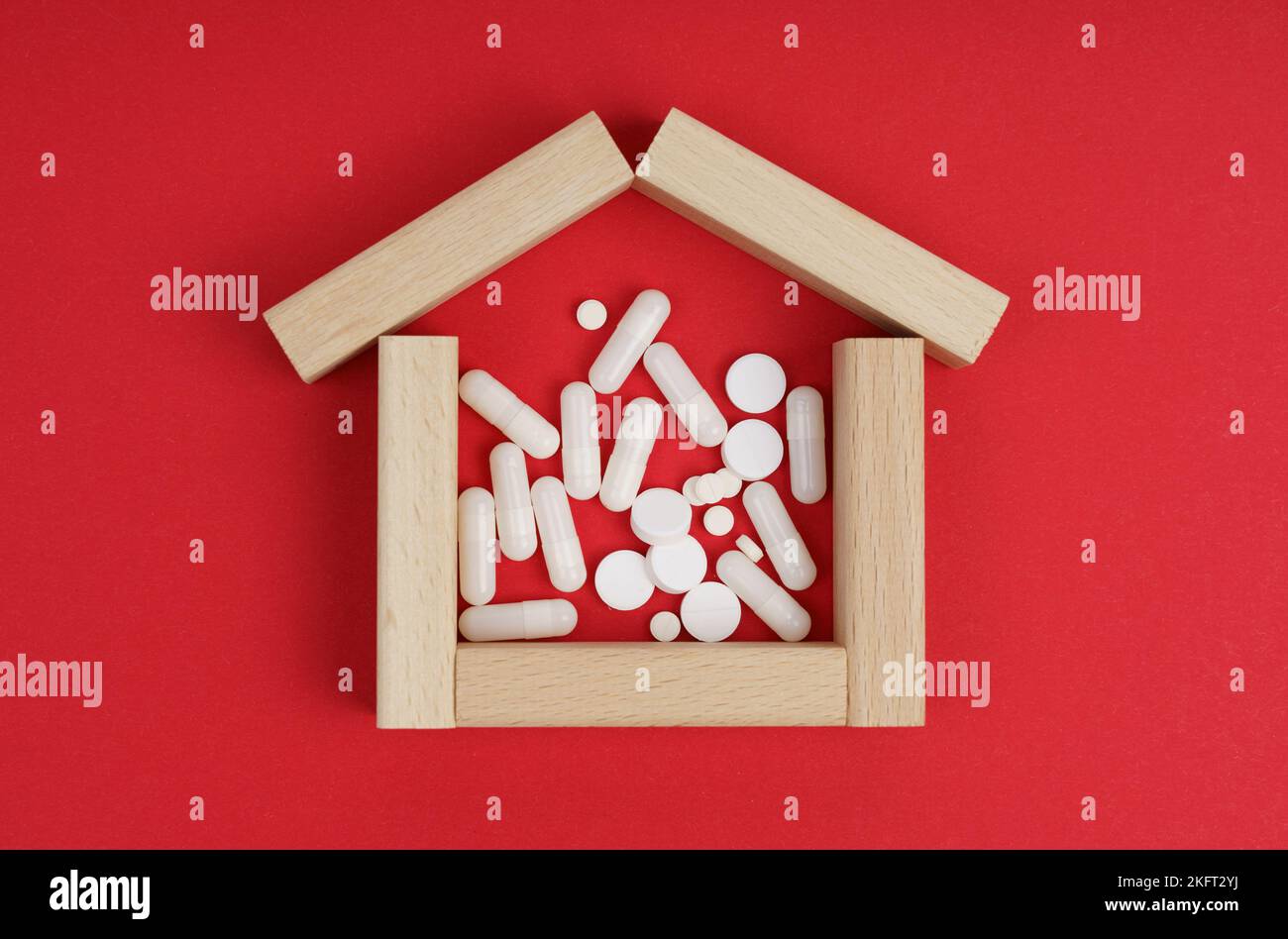 Medical concept. On a red background, a small house made of wooden ...