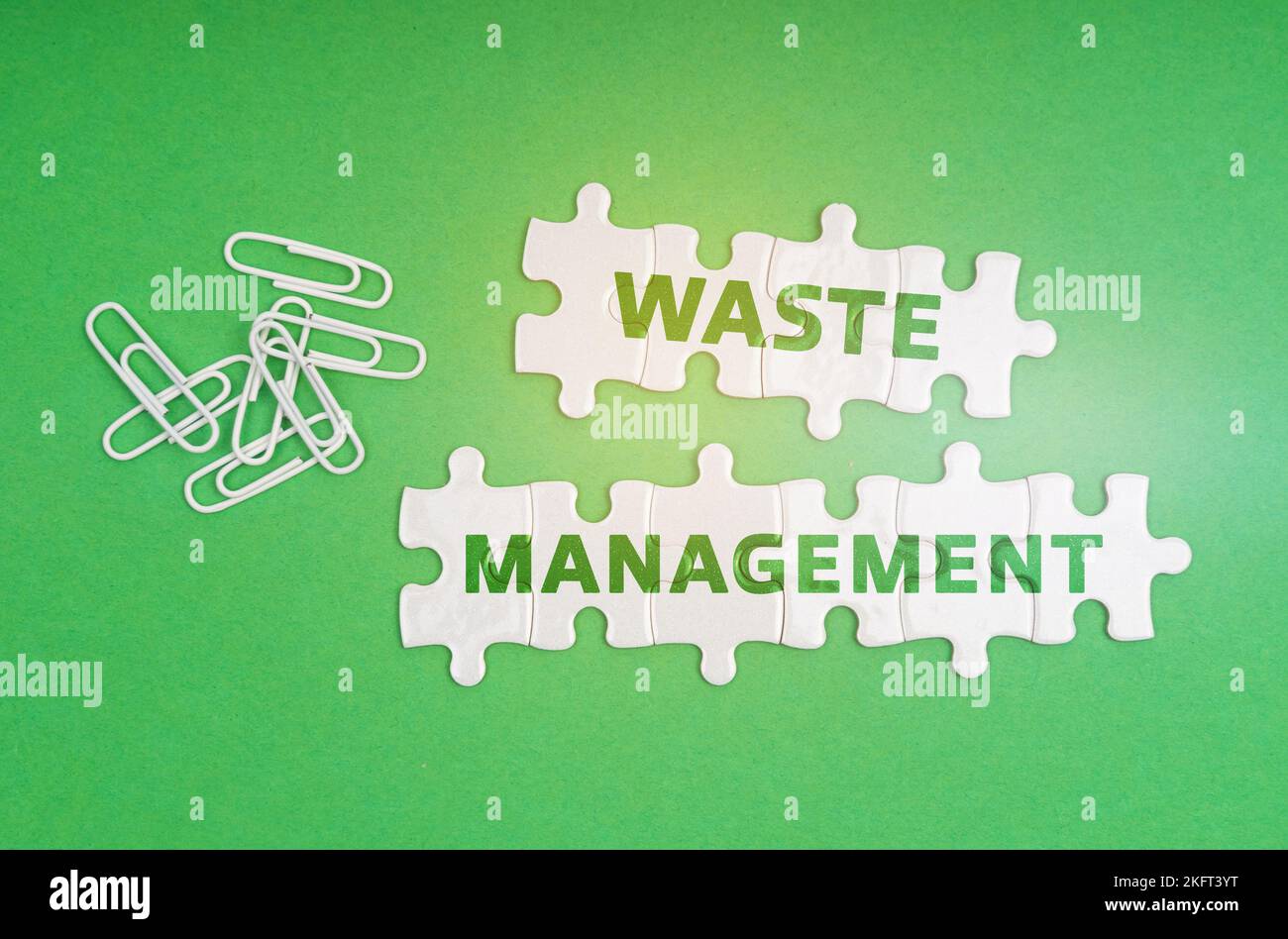 Ecology concept. On a green background, paper clips and white puzzles ...
