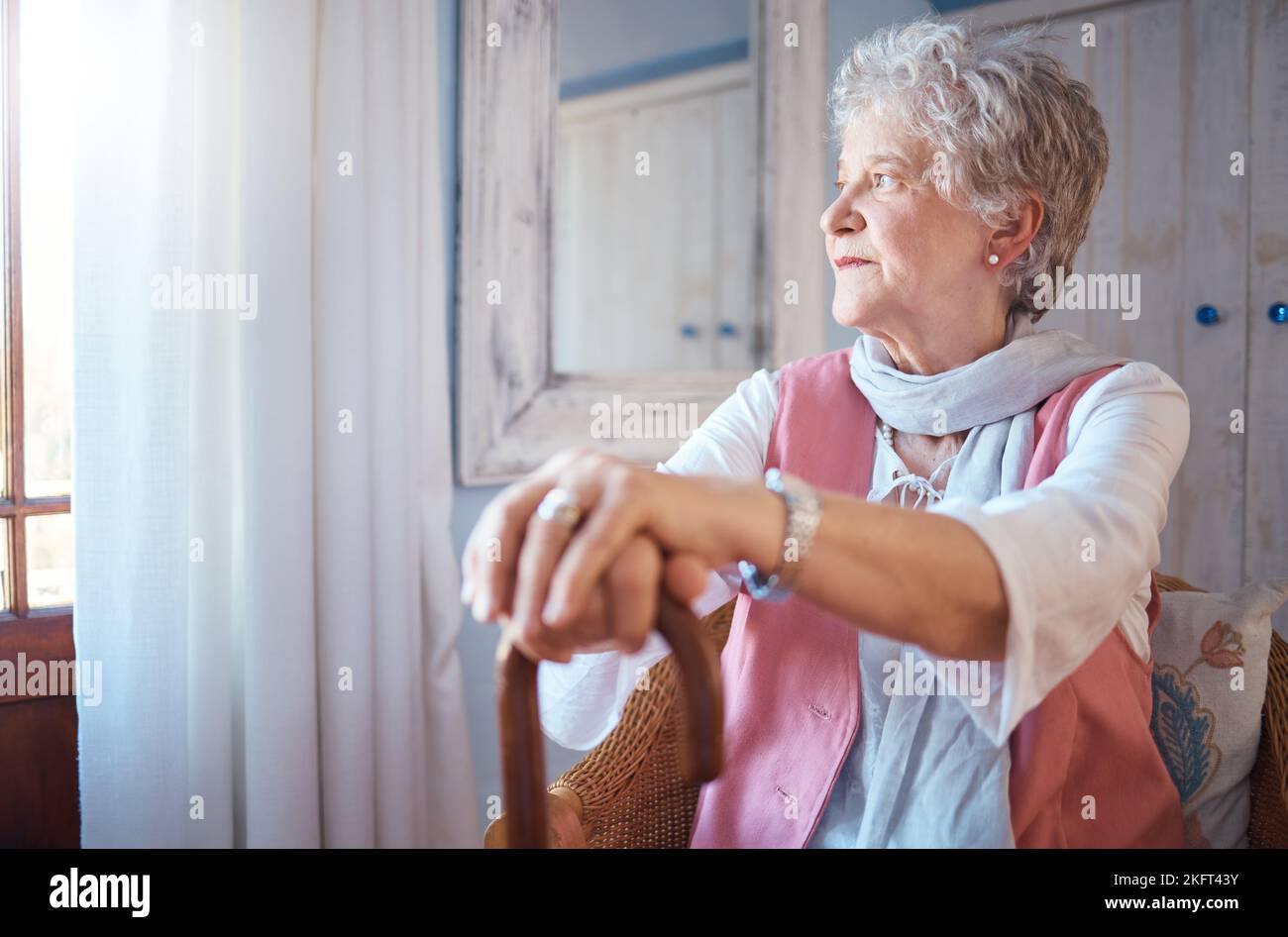 Senior woman, cane and thinking in home, nostalgic or contemplating old memory. Disability ...