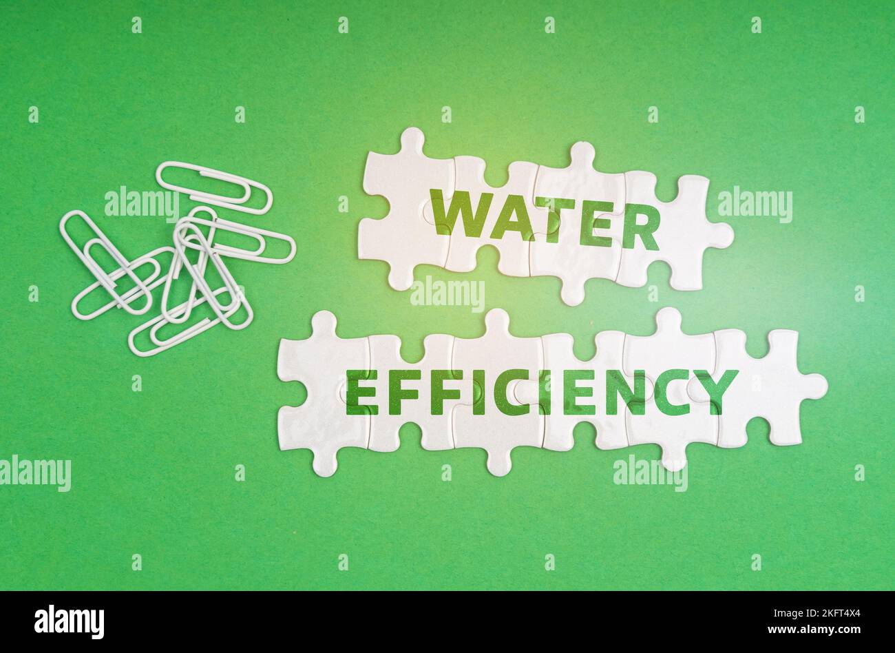 Ecology concept. On a green background, paper clips and white puzzles ...