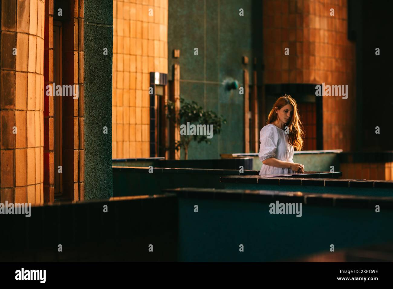 Female model walking on balcony with green walls against geometric huge ...
