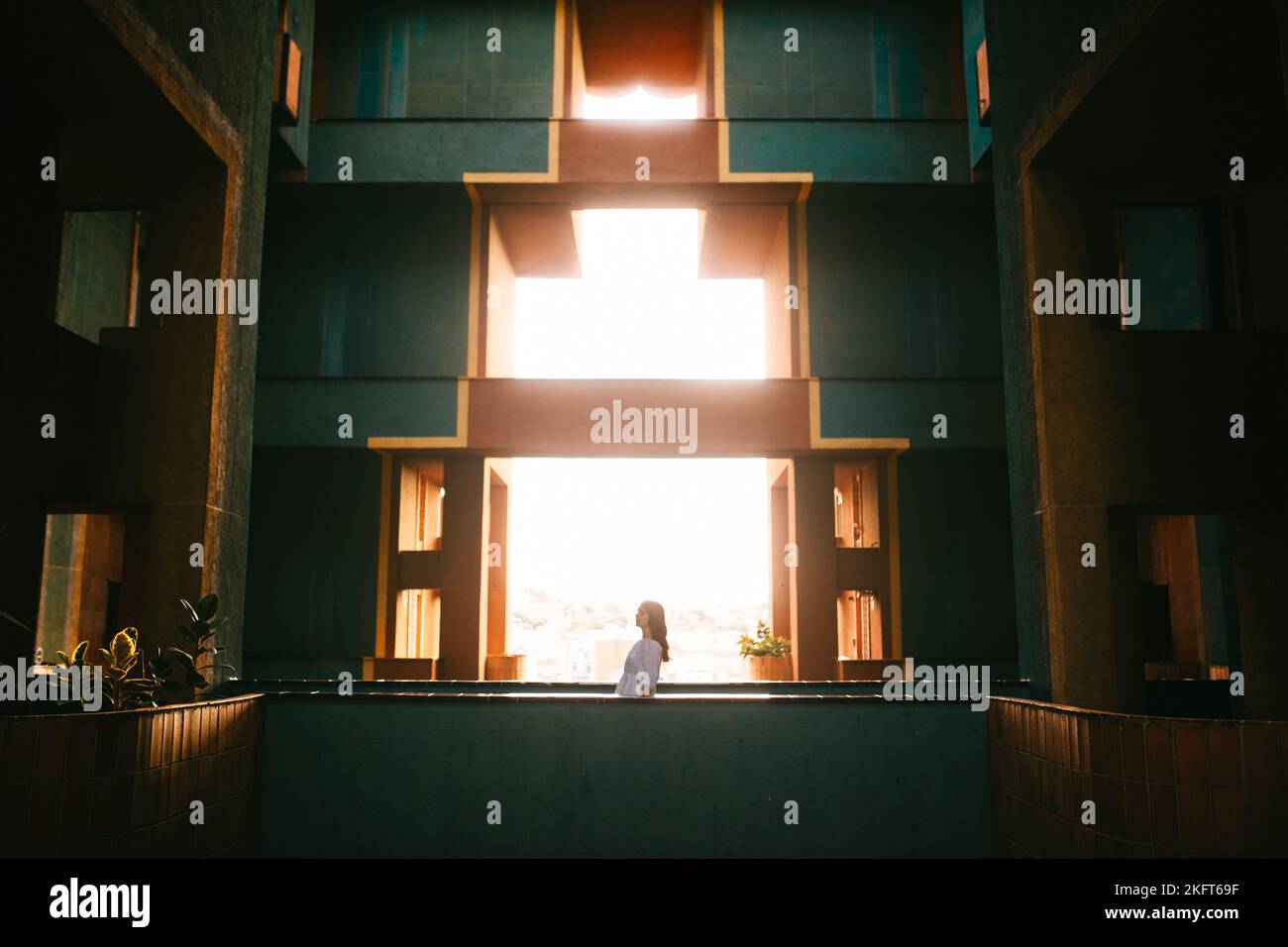 Side view of female model walking on balcony with green walls against ...