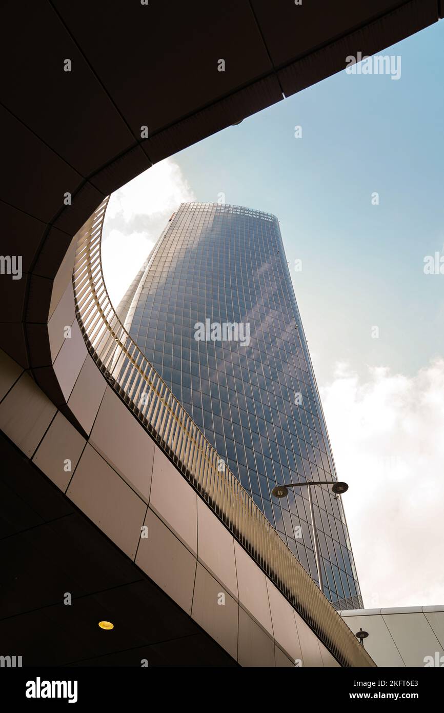 From below curvy modern high rise building with spire located against ...