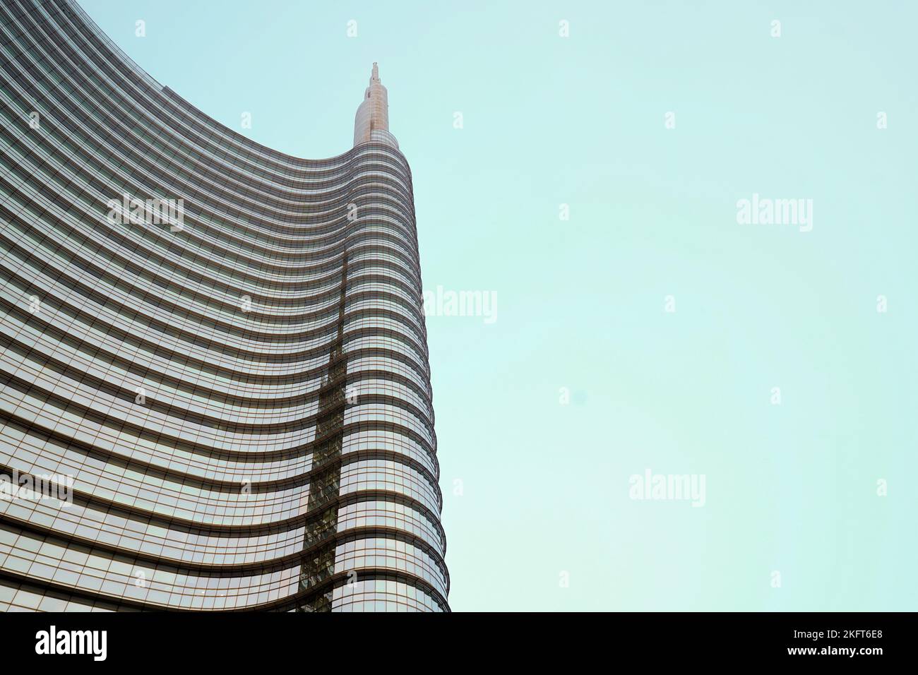 From below curvy modern high rise building with spire located against ...