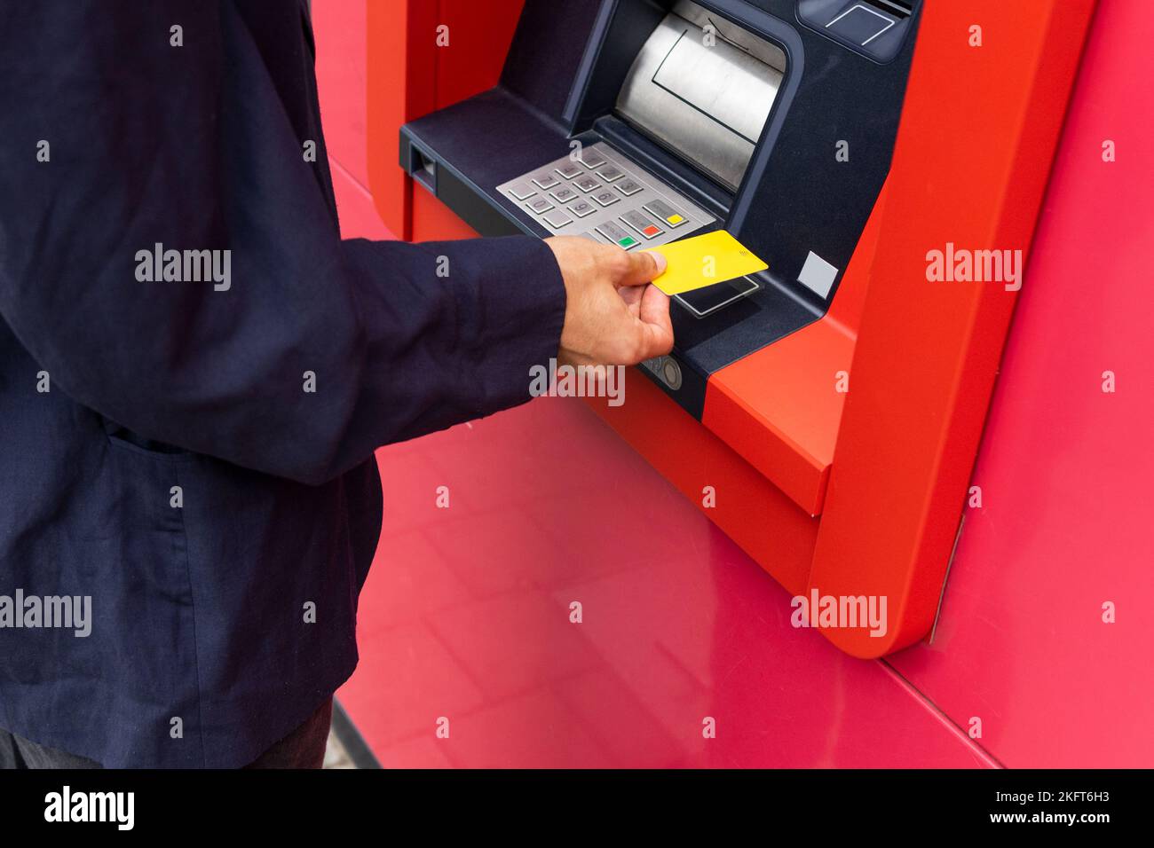 From above anonymous male using blank contactless credit card on ATM ...