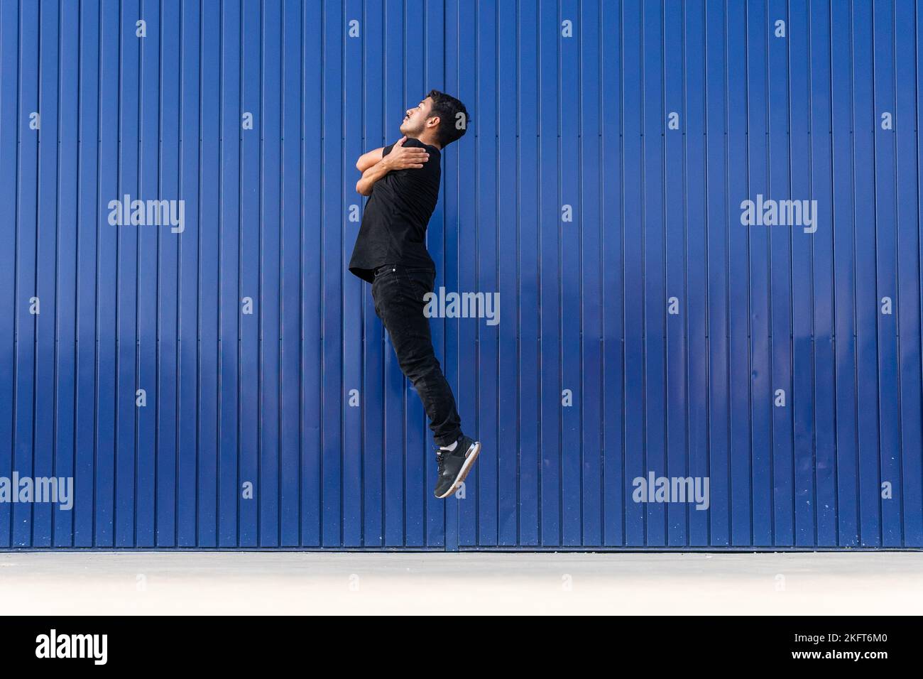 Side view full body of active male dancer jumping on street while ...