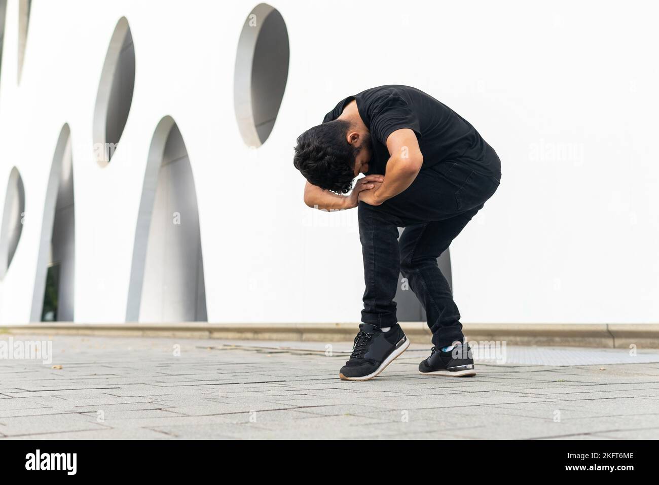 Focused male dancer in black casual outfit performing bending dance ...