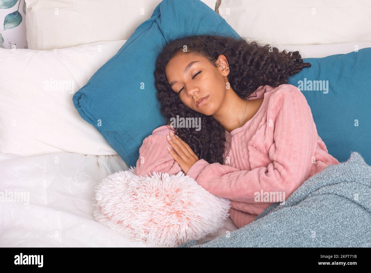 Young Latin American female zoomer with dark hair in pajamas lying on ...