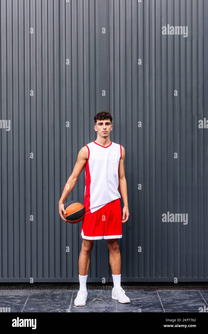 Portrait of full body serious man in activewear with ball standing ...