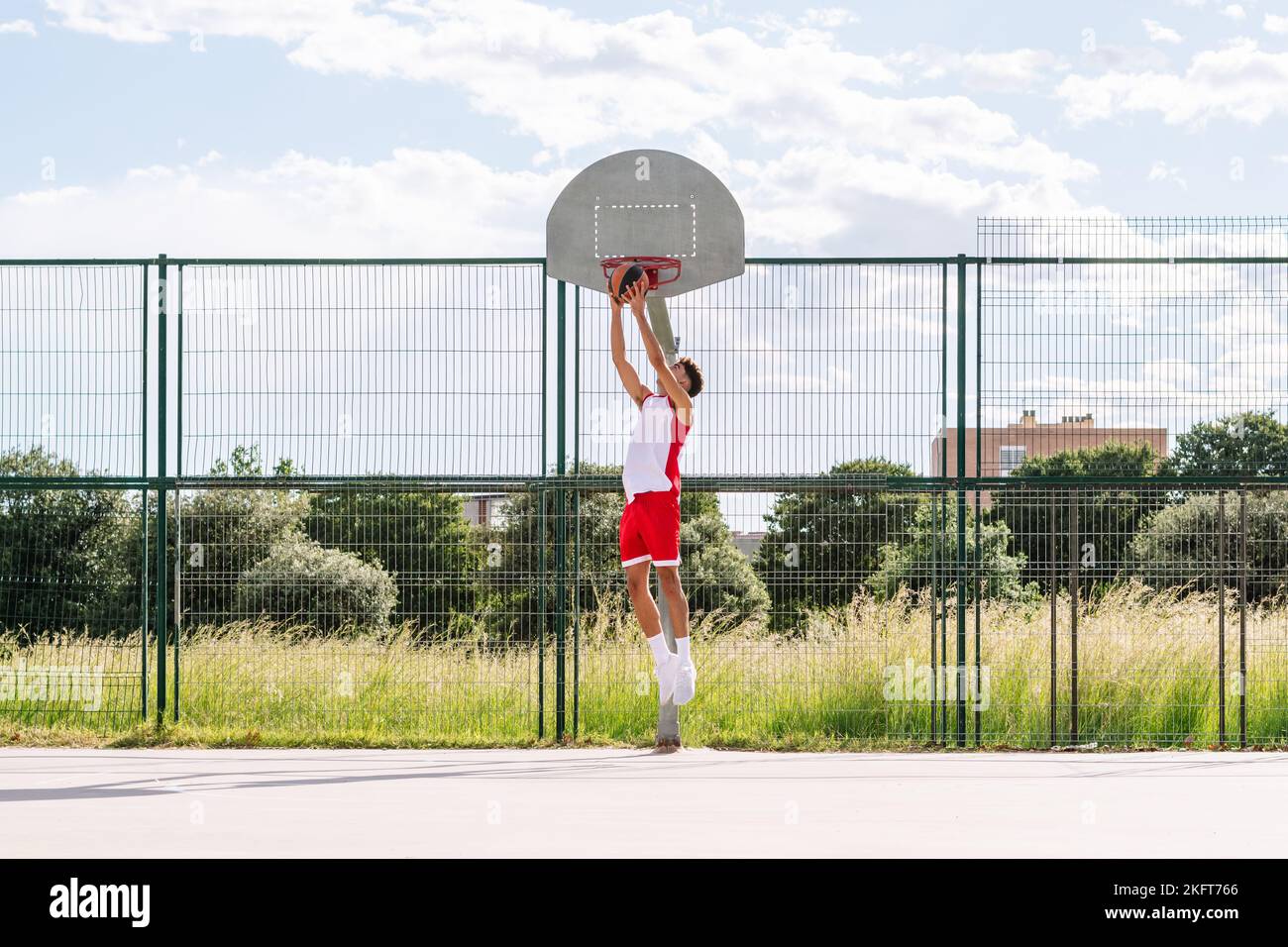 From below young sportsman throwing ball into basket while training ...