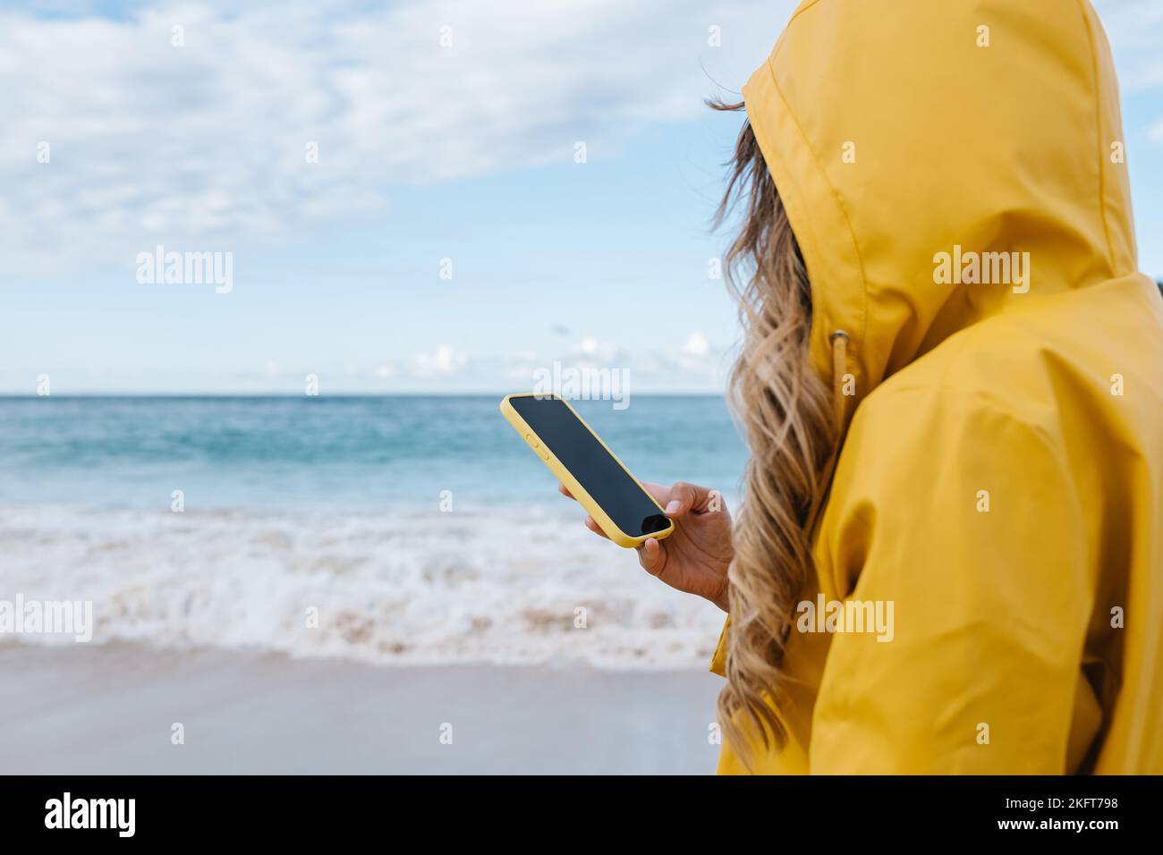 Side view of anonymous female with long blond hair in yellow raincoat ...