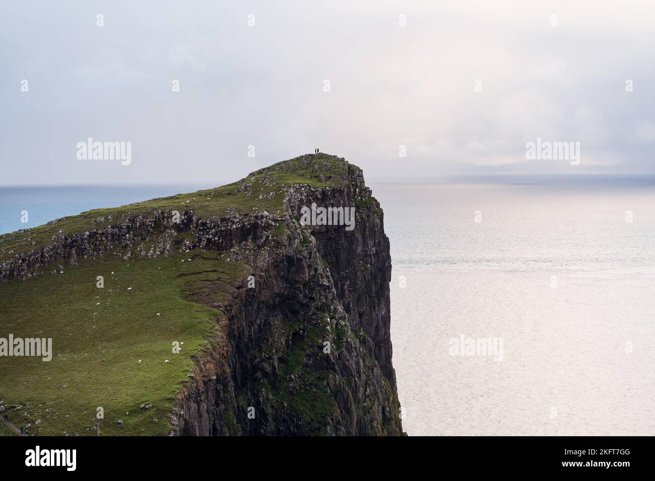 Anonymous People standing on rocky hill looking at endless blue sea ...