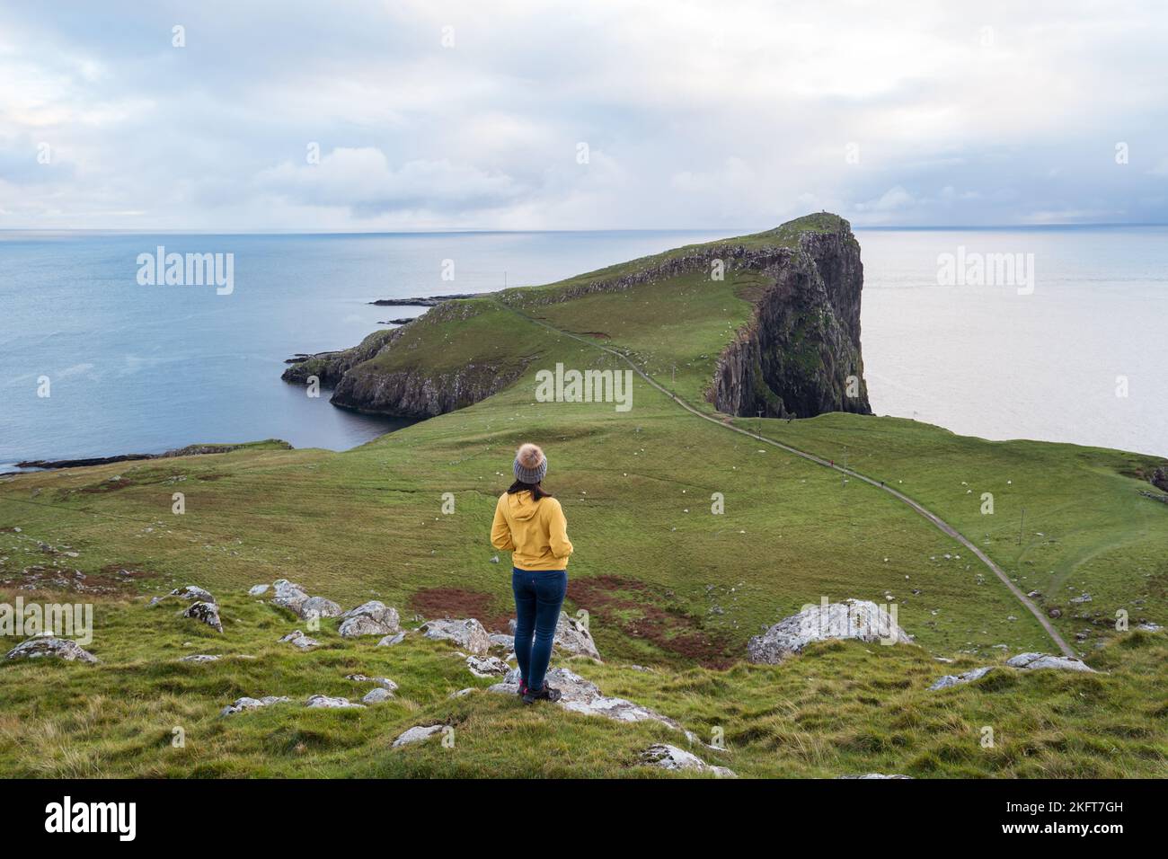 Full body back view of female standing on rocky hill with hands in ...